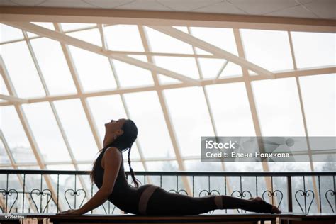 갈색 머리 여자 요가 개념 코브라 운동에서 스트레칭 테이블 상단 큰 창 앞에 Bhujangasana 포즈 연습 밖으로 전체 길이 운동복을 입고 일하고입니다 러시아에 대한