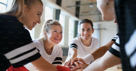 체육관에서 젊은 여성과 노인 여성이 손을 모으고 스포츠 팀 선수 체육관에서 승리를 축하하는 젊은이와 노인 여성 그룹 스포츠 팀 선수 젊고 오래된 여성 농구 팀 선수