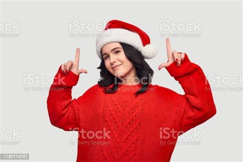 빨간 스웨터와 산타 모자에 예쁜 소녀는 회색 배경 위에 복사 공간을 가리키는 12월에 대한 스톡 사진 및 기타 이미지 12월 가리키기 겨울 Istock