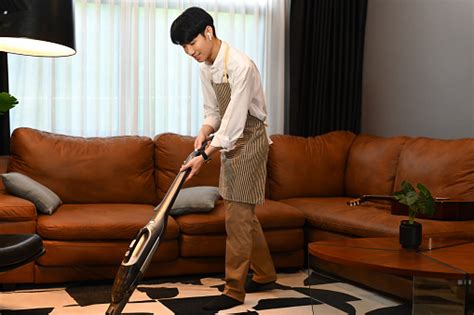 앞치마를 두르고 집에서 카펫을 진공 청소기로 청소하고 집안일을 하는 잘생긴 남자의 전체 길이 20 24세에 대한 스톡 사진 및 기타 이미지 Istock
