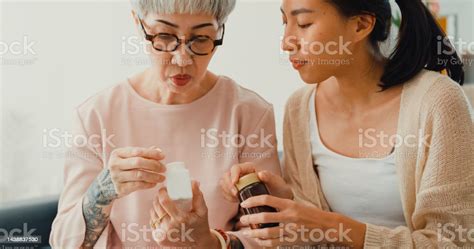 행복한 아시아 가족 어린 딸 및 노인 엄마는 의학 종합 비타민 병을 들고 나이든 어머니에게 집에서 약 약을 복용하는 방법을 가르칩니다 가족에 대한 스톡 사진 및 기타 이미지