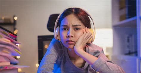 스트레스가 많은 젊은 아시아 여성은 헤드셋을 끼고 의자에 앉아 탁자 위에 서류 더미를 놓고 밤에 컴퓨터 화면을 보고 있다 사진 Unsplash의 성인 이미지
