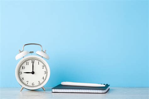 흰색 알람 시계 밝은 파란색 벽 배경에 나무 테이블에 펜플래너 시간 개념을 계획합니다 근접 촬영 텍스트의 빈 장소입니다 전면 보기입니다 배경 주제에 대한 스톡 사진 및 기타