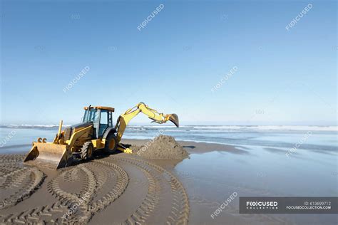 A Backhoe Digger With Large Scoop Working On The Soft Sand At The