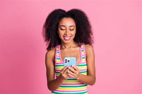 물결 모양의 머리를 한 사랑스러운 똑똑한 소녀의 초상화 화려한 옷을 입고 분홍색 배경에 고립 된 스마트 폰에서 알림 읽기 25