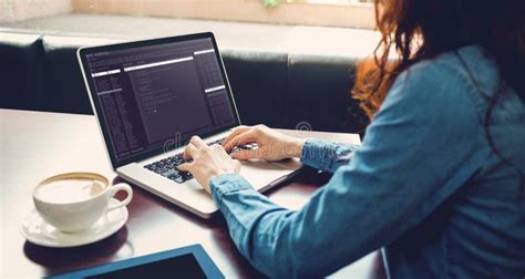 Midsection Of Caucasian Female Programmer Sitting At Desk And Using Laptop With Coding On Screen