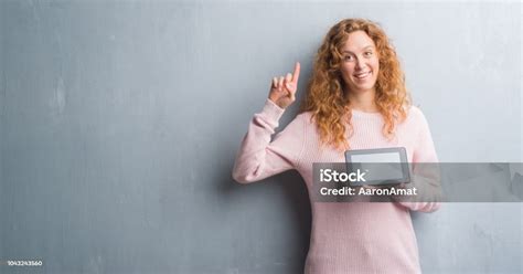 회색 그런 지 이상 젊은 빨강 머리 여자 아이디어 놀된 태블릿을 사용 하 여 벽 또는 행복 한 얼굴 넘버 원 가리키는 손가락 질문 미소에 대한 스톡 사진 및 기타 이미지