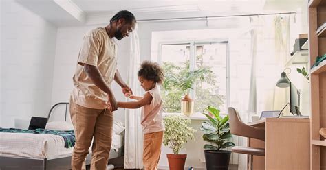 예쁜 곱슬 머리 소녀의 전체 길이 보기는 그녀의 아빠와 함께 춤을 즐기고 있습니다 그들은 침실의 바닥에 서서 재미있게 놀고 있습니다 사진 Unsplash의 실내 이미지