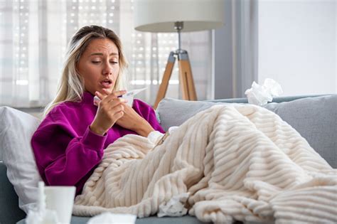 질병 계절 바이러스 문제 개념 온도계의 온도를 보고 소파에 누워 독감에 걸린 여자 고열로 침대에 누워 아픈 여자 감기 독감과
