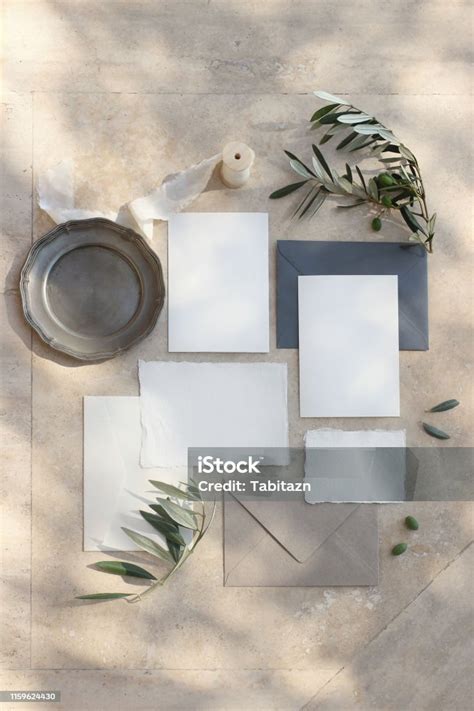 여름 웨딩 문구 모형 장면입니다 빈 인사말 카드 봉투 실버 플레이트 실크 리본과 햇빛에 올리브 가지 그림자대리석 배경입니다 수직 페미닌 플랫 레이 탑 뷰 결혼식에 대한 스톡