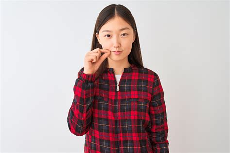 고립 된 흰색 배경 입과 입술 위에 서있는 캐주얼 재킷을 입은 젊은 중국 여성은 손가락으로 지퍼로 닫습니다 비밀과 침묵 금기 이야기 여자만에 대한 스톡 사진 및 기타 이미지