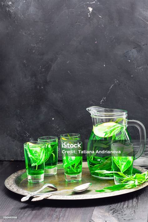 여름에는 차가운 녹색으로 타 라 곤 민트 레몬을 유리 디 켄 터로 마시고 얼음으로 작은 샷을 집중 하 여 초점을 맞출 것입니다 스파클링 음료 어두운 배경에 알코올 음료 수직