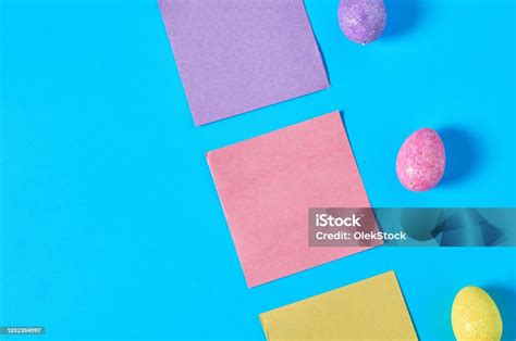 빈 사각형 종이 스티커 근처 반짝이 세 다채로운 계란부엌에 파란색 책상에 놓여있다 부활절 개념입니다 텍스트의 공백입니다 맨 위 보기 3가지 개체에 대한 스톡 사진 및 기타