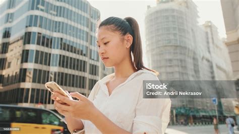 젊은 여자는 도로 옆에 서서 휴대 전화를 사용합니다 택시를 기다리는 소녀 가까운에 대한 스톡 사진 및 기타 이미지 가까운