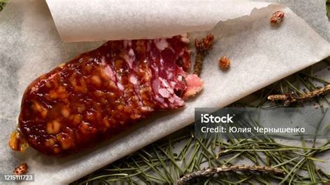 비버 고기로 만든 말린 소시지 소나무 싹 클로즈업으로 양피지에 슬라이스로 잘라 소나무 바늘로 만든 바닥 블록에 대한 스톡 사진