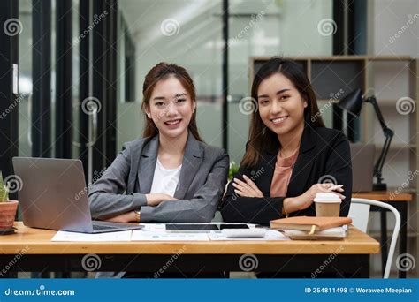 Two Positive Asian Secretary Smiling To Camera During Meeting At Office