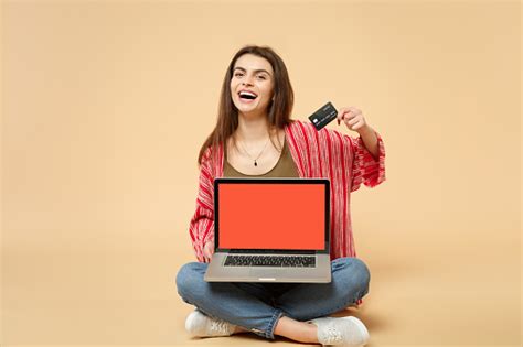 앉아 젊은 여자를 웃 고 신용 은행 카드를 들고 파스텔 베이 지 배경에 고립 된 빈 빈 화면으로 노트북 Pc 컴퓨터 사람들은 진심으로 감정 라이프 스타일 개념입니다 복사