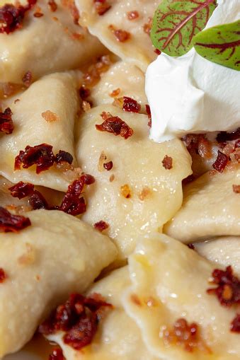 감자 사워 크림 양상추 잘게 썬 튀긴 베이컨을 곁들인 Vareniki 음식은 흰색의 둥근 세라믹 접시에 놓여 있습니다 접시는 어두운 배경 커피 색상에 서 있습니다 0명에