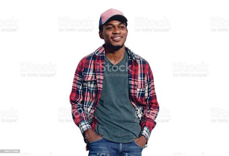 야구 모자를 쓰고 포즈를 취하는 세련된 미소 짓는 젊은 아프리카 남자의 초상화 흰색 배경에 고립 된 빨간 격자 무늬 셔츠