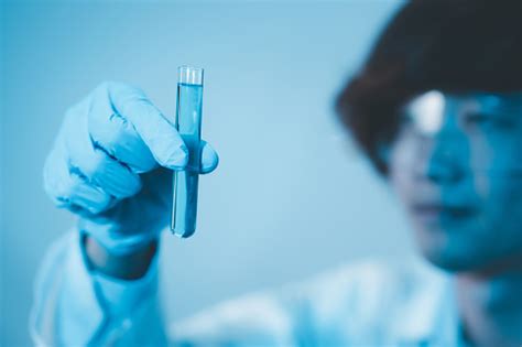 과학자는 화학 과학 실험실에서 파란색 샘플 화학 물질로 채워진 시험관을 손에 들고 있습니다 의학 연구의 유리 제품 생명 공학 과학 실험실 25 29세에 대한 스톡 사진 및