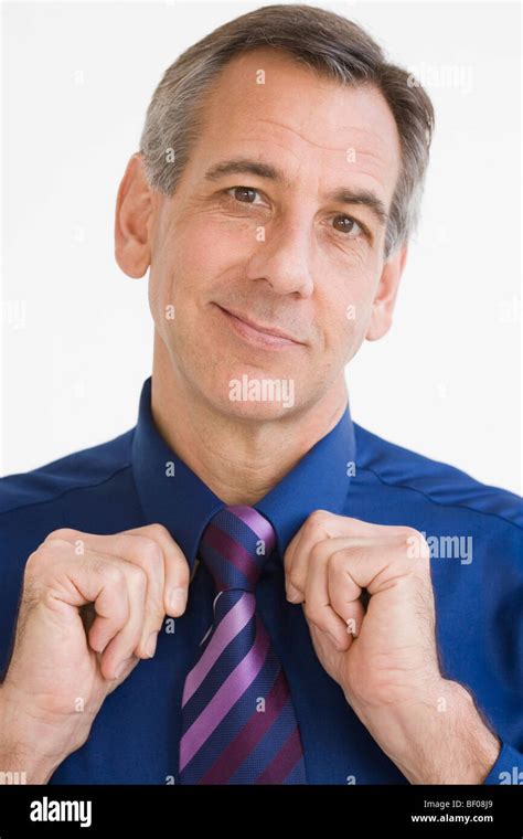 Portrait Of A Businessman Adjusting His Tie And Smirking Stock Photo