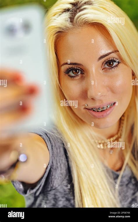 Vertical Portrait Of Young Blond Woman In Selfie Position Fixes The Lens With Intense Eye