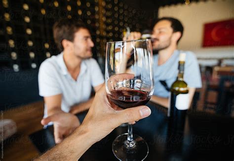 First Person View Of Hand Holding Wine Glass And People Drinking Wine