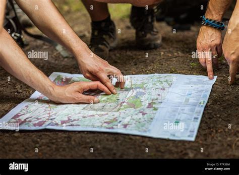 A Group Of Hikers Uses Map And Compass To Navigate Through The Forest
