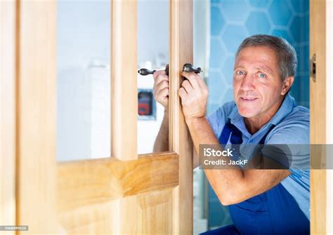 실내에서 개조 중에 문에 문 손잡이를 설치하는 제복을 입은 전문 중년 수리공 열쇠집에 대한 스톡 사진 및 기타 이미지 열쇠집 핸디맨 전문 기술 Istock