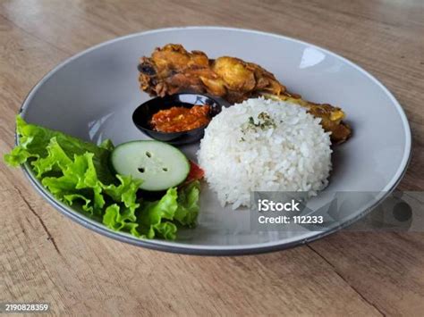 맛있는 나시 아얌 고렝 누산타라는 특별한 향신료로 절인 닭고기입니다 흰 쌀밥 양상추 오이 칠리 소스와 함께 제공됩니다 인도네시아 음식 메뉴 0명에 대한 스톡 사진 및 기타