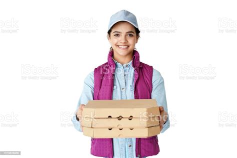 흰색 스튜디오 배경에 고립 된 피자를 전달하는 손에 상자를 들고 카메라를보고 유니폼과 모자를 입고 젊은 히스패닉 여성 택배 미소 피자 음식 배달 개념입니다 배달부에 대한