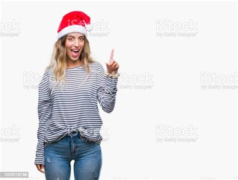 이상의 크리스마스 모자를 입고 아름 다운 젊은 금발의 여 자가 성공적인 아이디어와 손가락 가리키는 배경 고립 종료 하 고 행복 번호 하나입니다 가리키기에 대한 스톡 사진 및