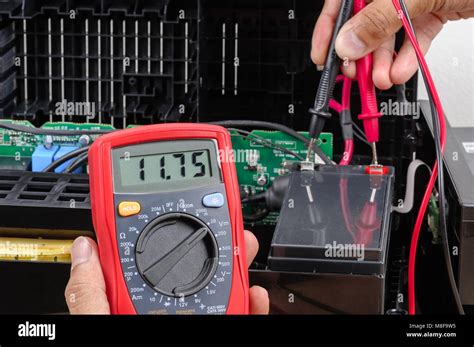 Technician Measuring The Voltage Of Battery For UPS Uninterruptible Power Supply With