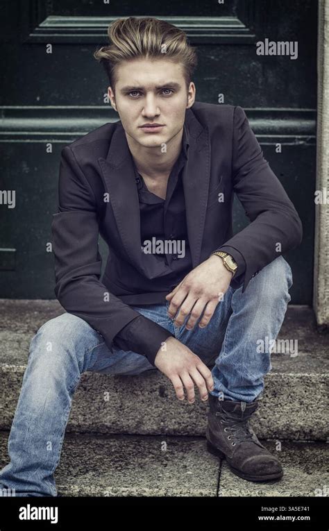 Handsome Blond Young Man Sitting On Stone Stair Steps Outside Of Big