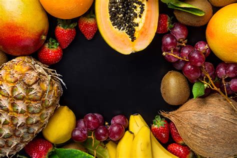 신선한 열 대 여름 제철 과일 파인애플 파파야 망고 코코넛 오렌지 키 위 바나나 레몬 자 몽 검은 배경에에서 복사 공간 프레임 건강 한 식물 근거한 규정식