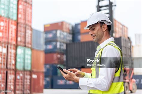 백인 잘 생긴 남자 엔지니어 노동자는 컨테이너 항구 터미널에서 일합니다 젊은 감독직 노동자는 항구에서 수입 및 수출을 위해화물화물선의 창고 물류에서 주문 및 제품을