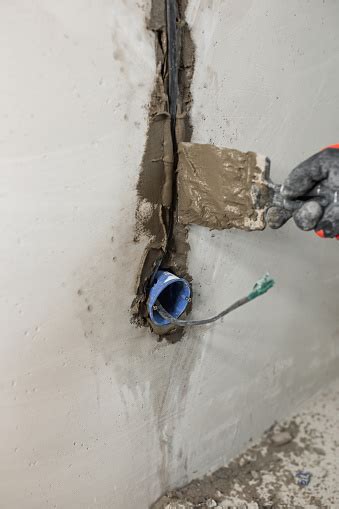 마스터 전기 기술자는 콘크리트 벽에 케이블을 놓고 전기 콘센트를 장착합니다 건설 산업에 대한 스톡 사진 및 기타 이미지 건설