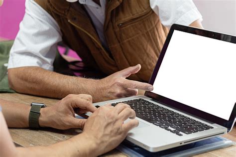 한 남자가 랩톱 컴퓨터의 빈 화면을 가리키고 다른 남자는 그것을 조작합니다 컴퓨터를 사용하여 프로젝트를 공동 작업하는 두 남자 먼지 투성이의 키보드 2명에 대한 스톡 사진