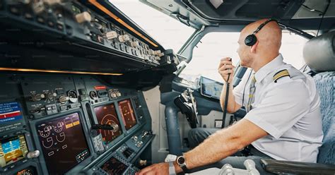 헤드폰을 끼고 조종석에 앉아 손에 라디오를 들고 시선을 돌리고 있는 전문 남성 조종사 사진 Unsplash의 성인 이미지