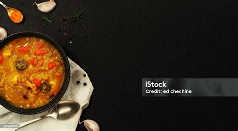 고기 당근 파프리카 심황을 곁들인 전통적인 완두콩 수프 검은 돌 배경에 수프 마늘의 정향 옆에 로즈마리와 심황의 잔가지 플랫 레이 자연 광 공간을 복사합니다 0명에 대한
