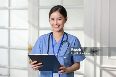팔짱을 끼고 카메라를 바라보며 미소 짓는 청진기 미소를 가진 아름 다운 아시아 여의사 간호사는 스크럽 미소를 입고 따뜻하고