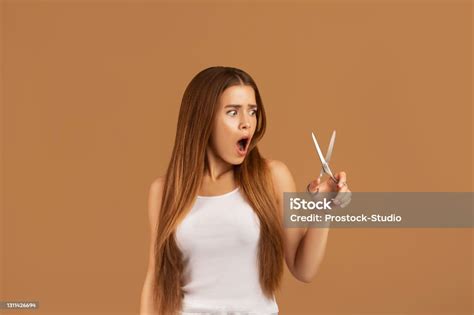 브라운 스튜디오 배경에 가위를 들고 긴 직선 머리와 충격 밀레니엄 여성 여자에 대한 스톡 사진 및 기타 이미지 여자 자르기 털 Istock