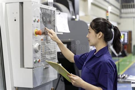 Asian Woman Industrial Engineer Wearing Uniform Hold A Clipboard Checking Of Automated Machinery