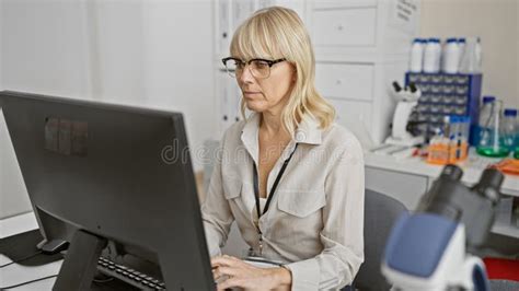 A Focused Blonde Woman Working On A Computer In An Indoor Laboratory Setting Stock Image Image