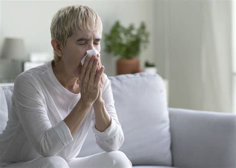Middle Aged Asian Woman Sick With Flu Or Cold Sneezing Into Tissue