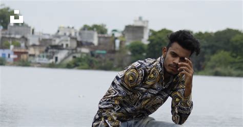 갈색과 검은색 위장 재킷과 파란색 데님 청바지를 입은 남자가 몸 근처의 바위에 앉아 있다 사진 Unsplash의 무료 초상 이미지