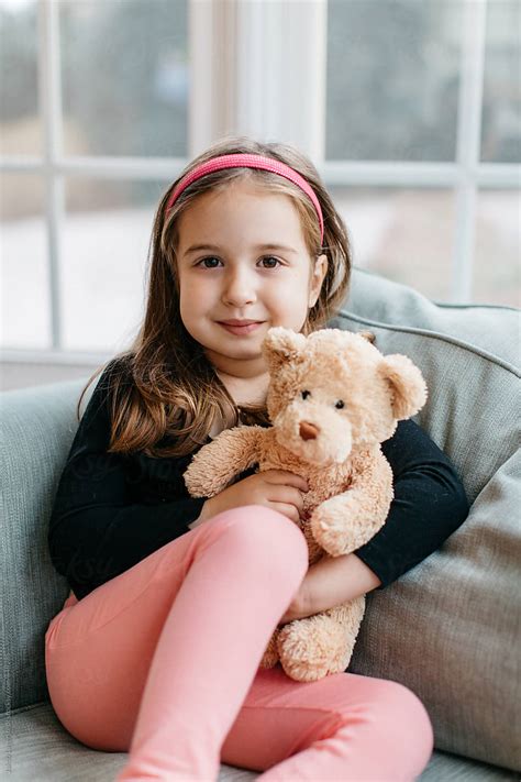 Beautiful Young Girl Sitting On A Big Chair With Her Teddy Bear By Stocksy Contributor Jakob