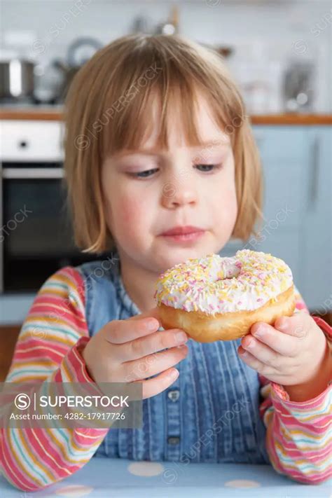 Young Girl Enjoying Eating Sugary Doughnut Superstock
