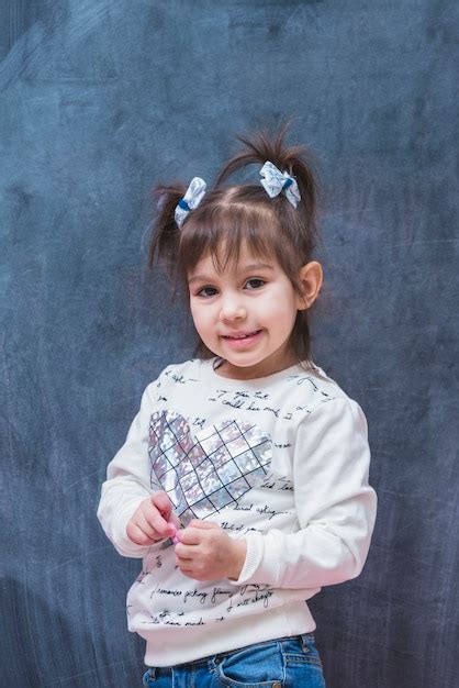 Kleines Mädchen Mit Schwänzen Durch Graue Wand Kostenlose Foto