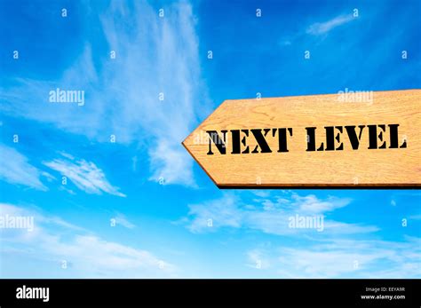Wood Arrow Sign Against Clear Blue Sky With Next Level Message Progress Conceptual Image Stock